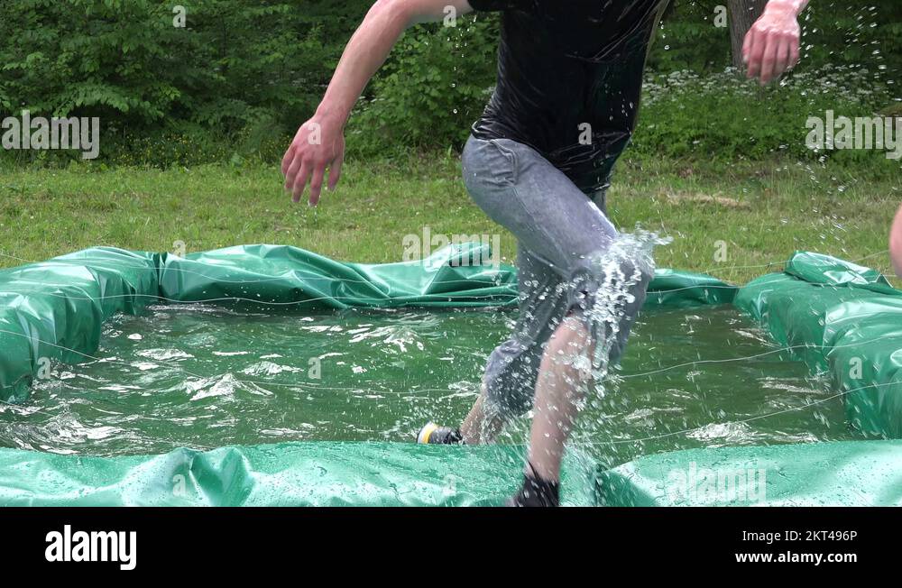 two young men compete diving in small water pool with hurdles. 4K Stock ...