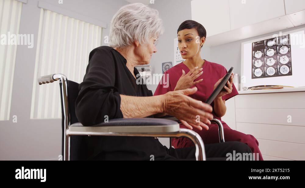 Young nurse talking to handicapped patient in a wheelchair Stock Video ...