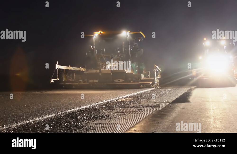 Tracked paver laying fresh asphalt pavement by night Stock Video ...