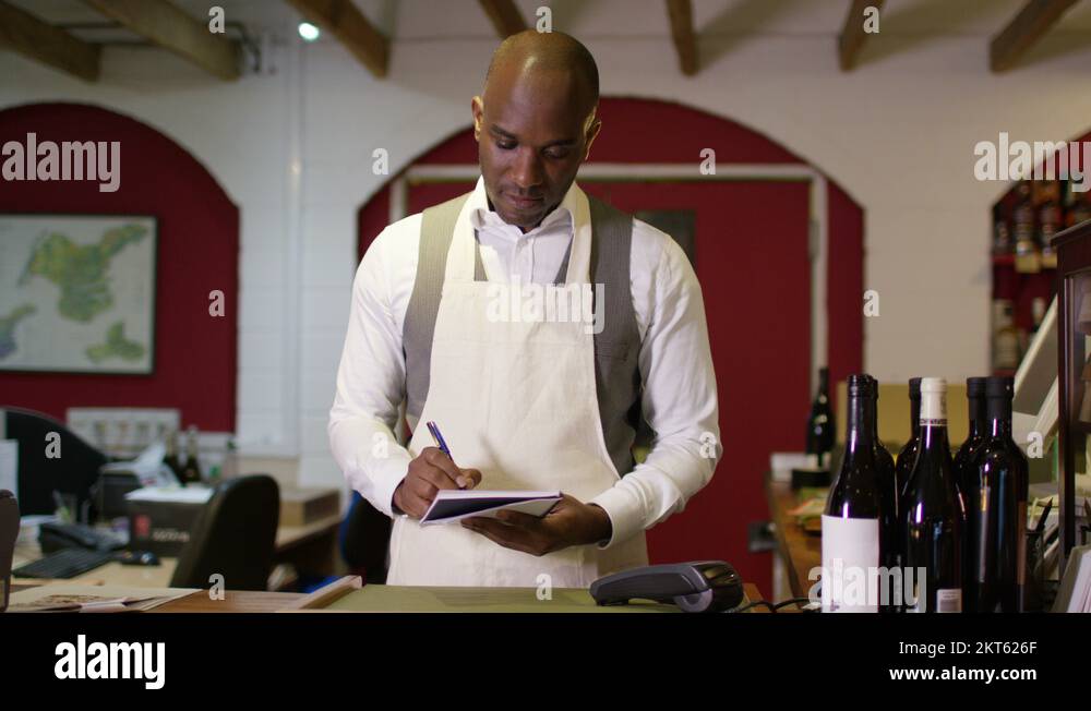 4K Portrait of friendly shopkeeper standing behind counter in wine shop ...