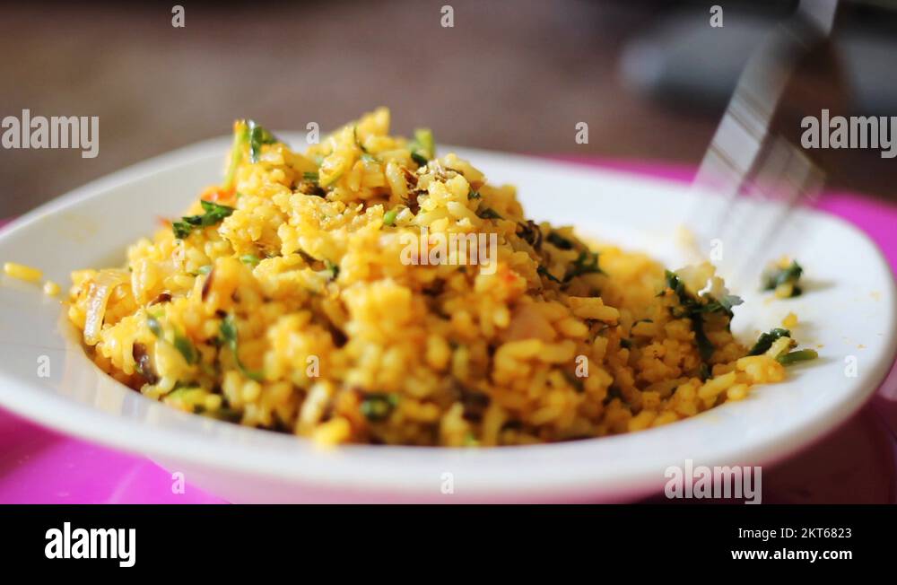 woman eats with a fork from steaming plate of Nigerian Jollof Rice ...