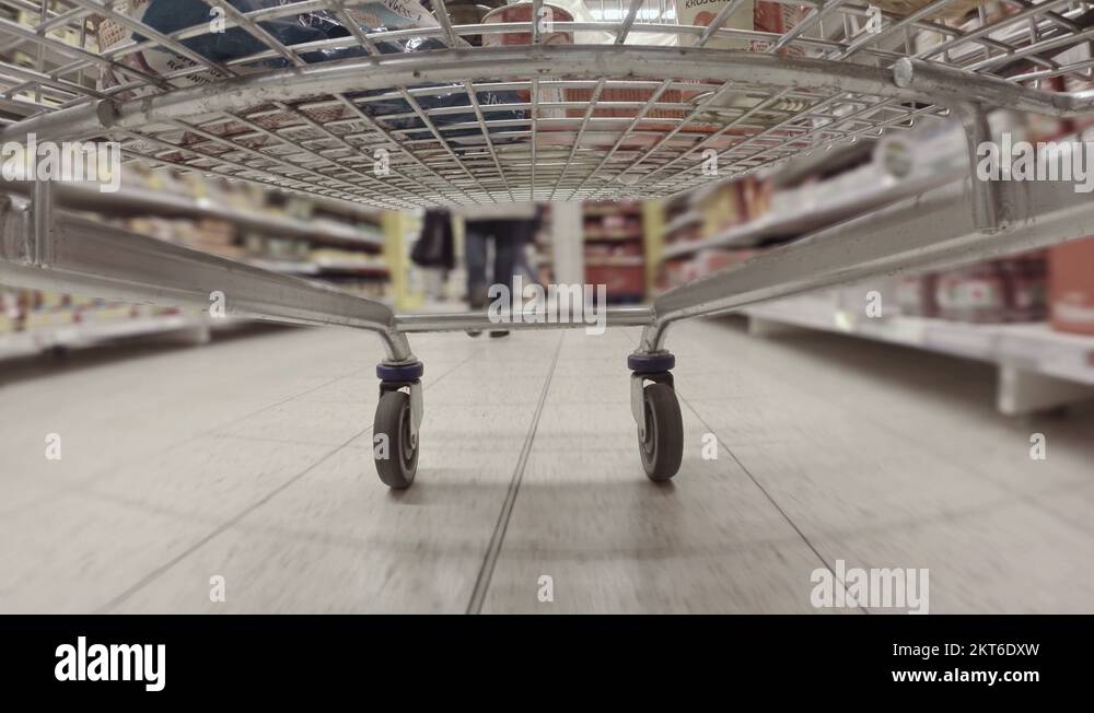 Shopping in supermarket stopping and starting trolley filling with ...