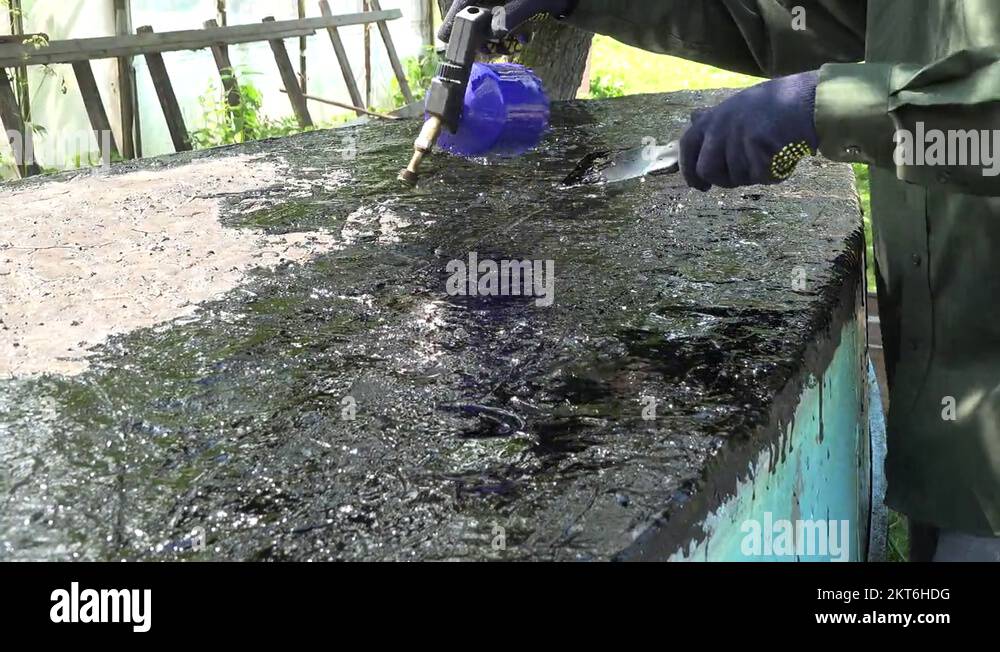 man hands with gas burner and hot tar repair his boat bottom in garden ...