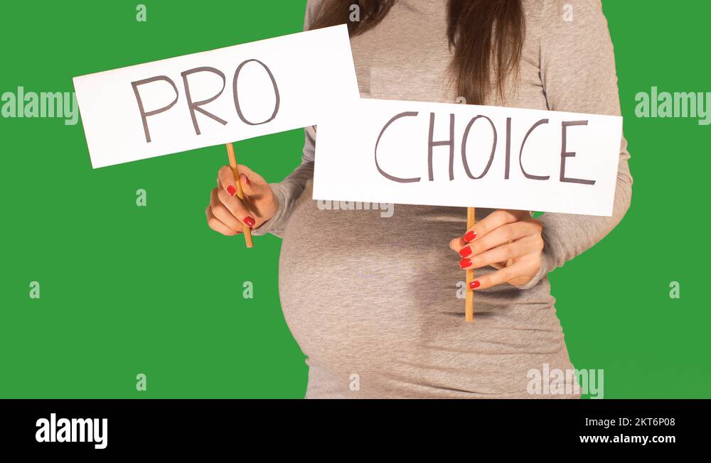 Pregnant woman holds Pro-Choice Pro-Life cards in front of green screen ...