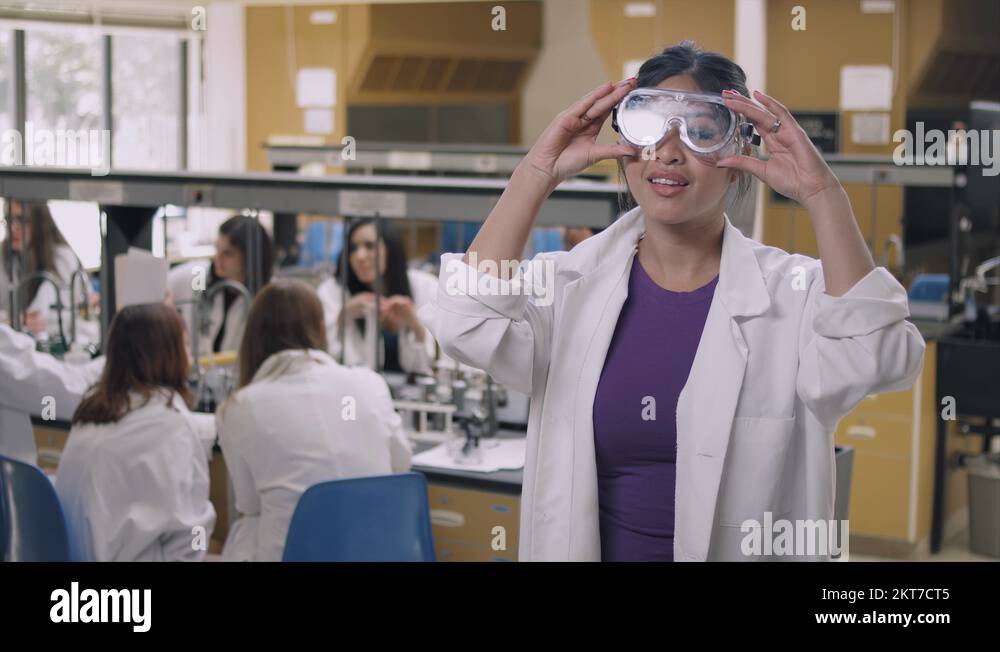 student in a science lab putting on safety goggles and smiling Stock ...