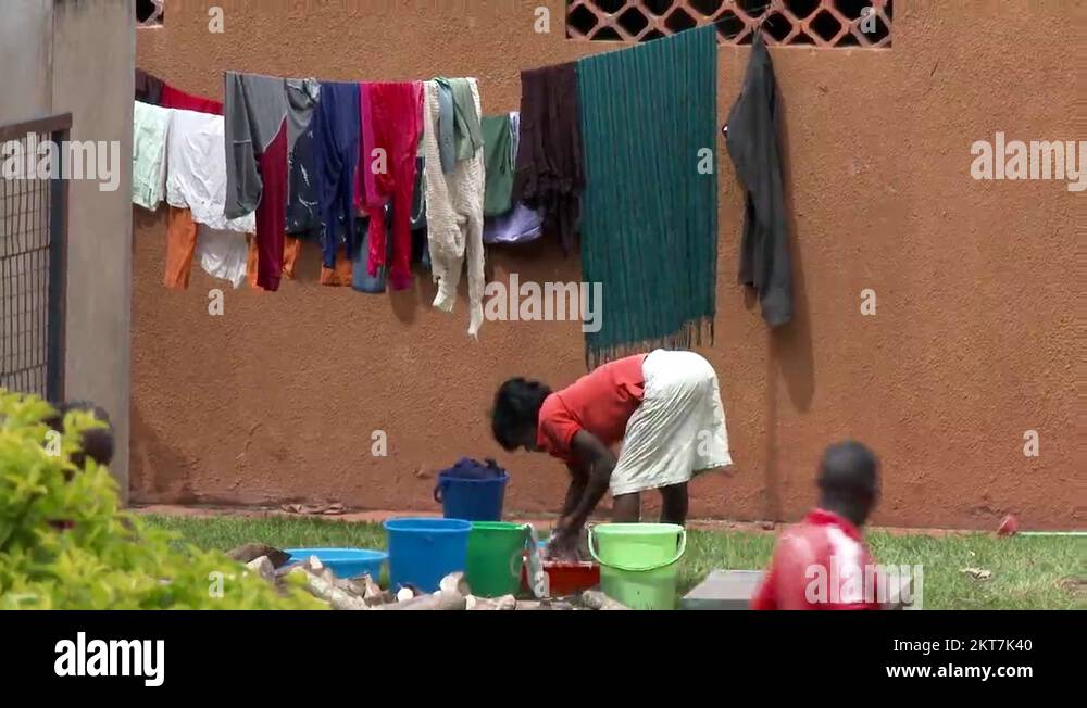 KAMPALA, UGANDA: African woman washing clothes by hand outside her ...
