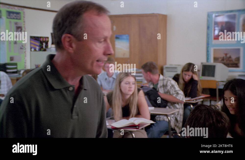 Teacher moving through classroom where seated students do an assignment ...