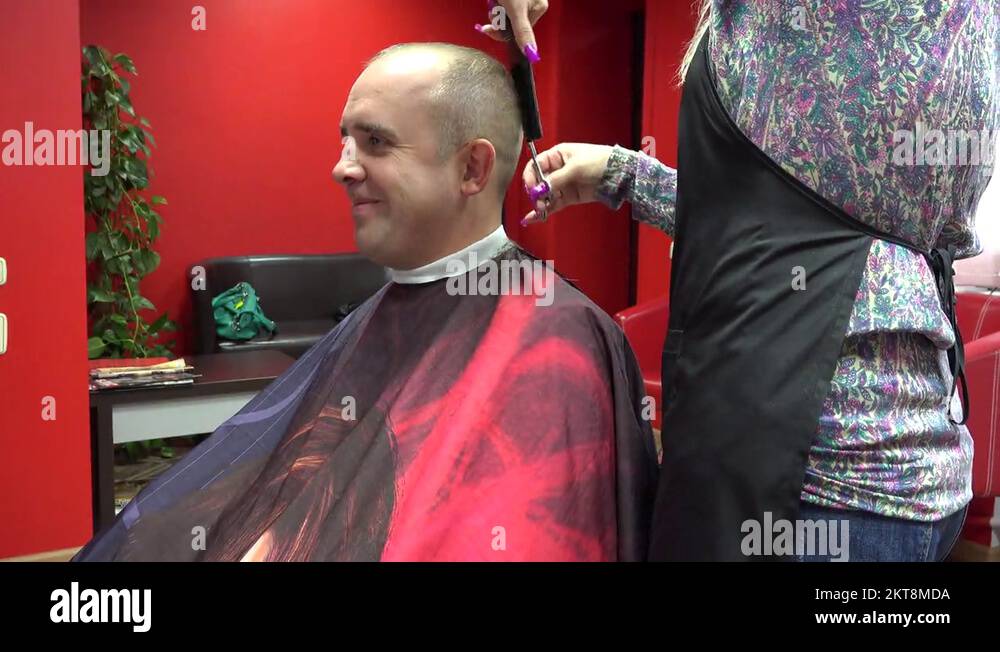 Hairdresser making haircut to young smiling man at beauty parlour. 4K ...