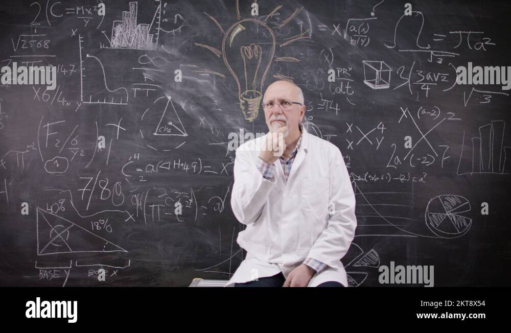 4K Portrait of thinking man sitting in front of blackboard with math ...