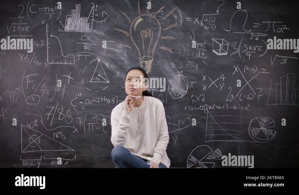 4K Portrait of thinking woman sitting in front of blackboard with math ...