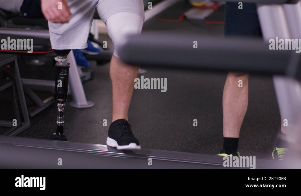 4K Man with prosthetic leg working out at the gym with personal trainer ...