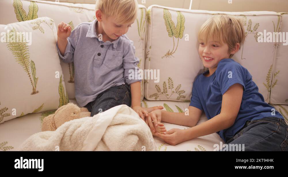Young blond boy tickling his brother's feet on a sofa Stock Video ...