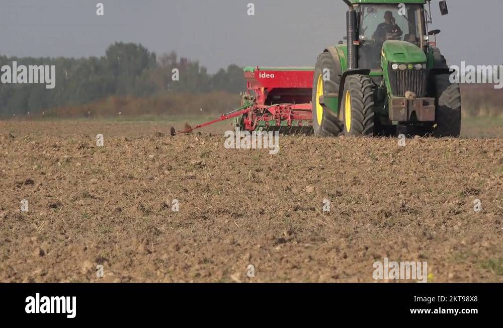 Brown field soil and blurred tractor with seeder work on background. 4K ...