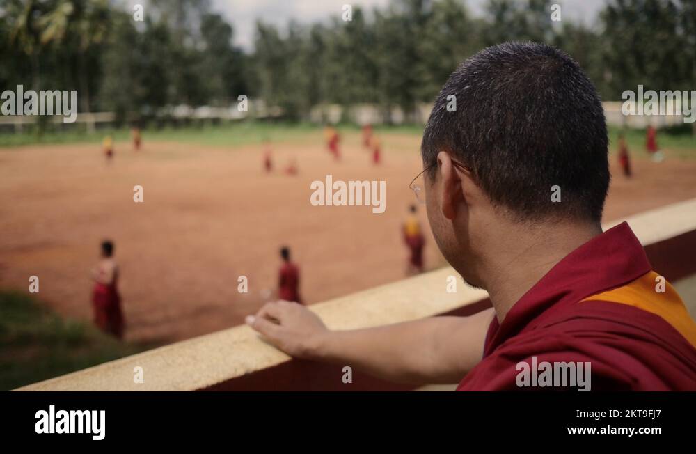 Happy Buddhist Monk teacher watching his students play on playground ...