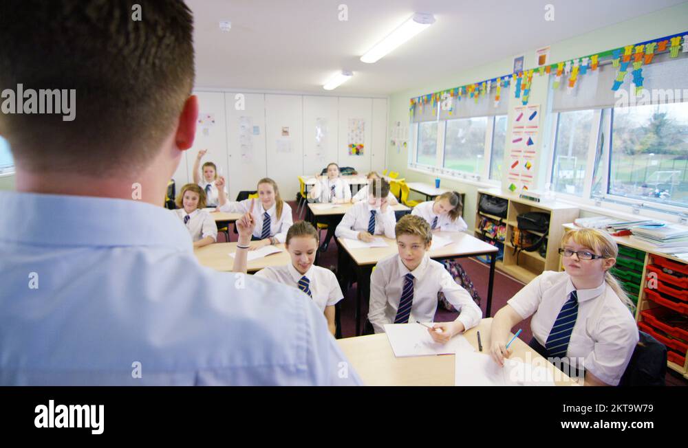 4K Young students listening to teacher & putting hands up in school ...