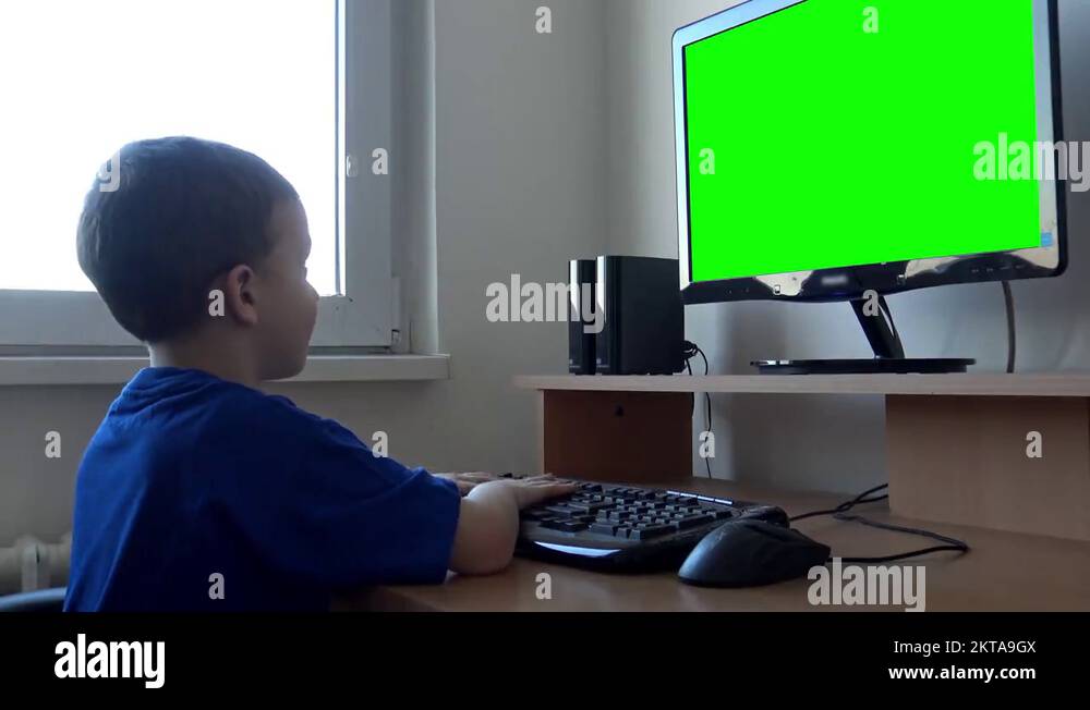 young child boy works on computer on the table in room - green screen ...
