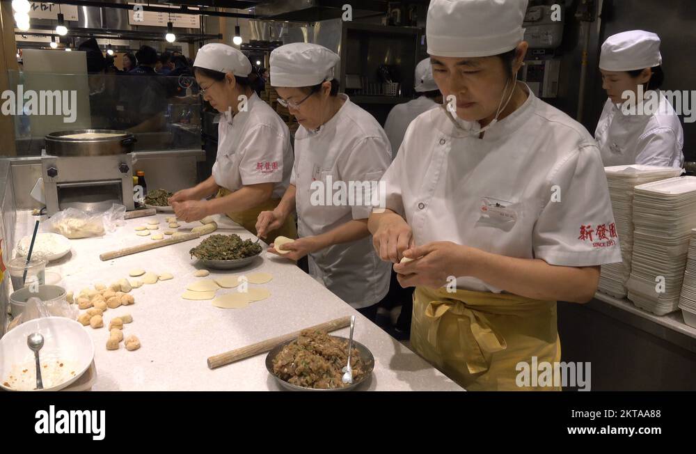 Asian chefs prepare fresh dumplings in a busy food court in South Korea ...