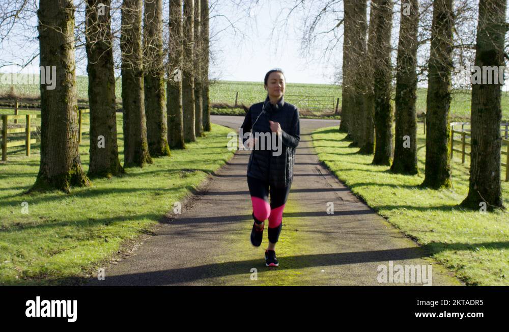 4K Young woman running in the countryside stops to get her breath back ...