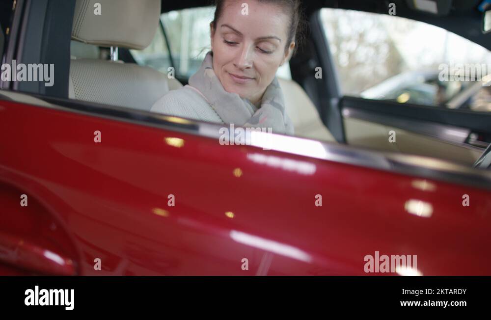 4K Salesman in car dealership showing customer the interior of new car ...