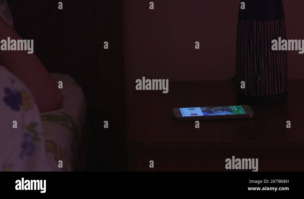 Sleeping woman on bed awakened by smart phone incoming call at night ...