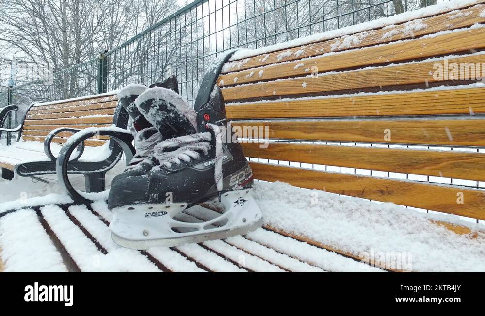 4k hockey skates sit on bench while it is snowing Stock Video Footage ...