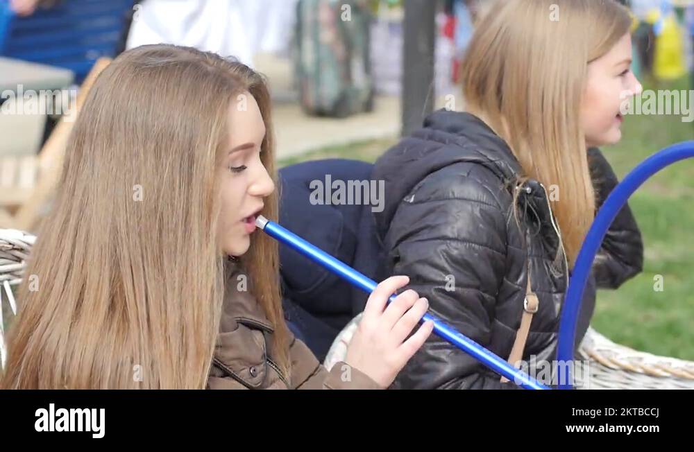 Young girl smoking hookah in slow motion in a street public place ...