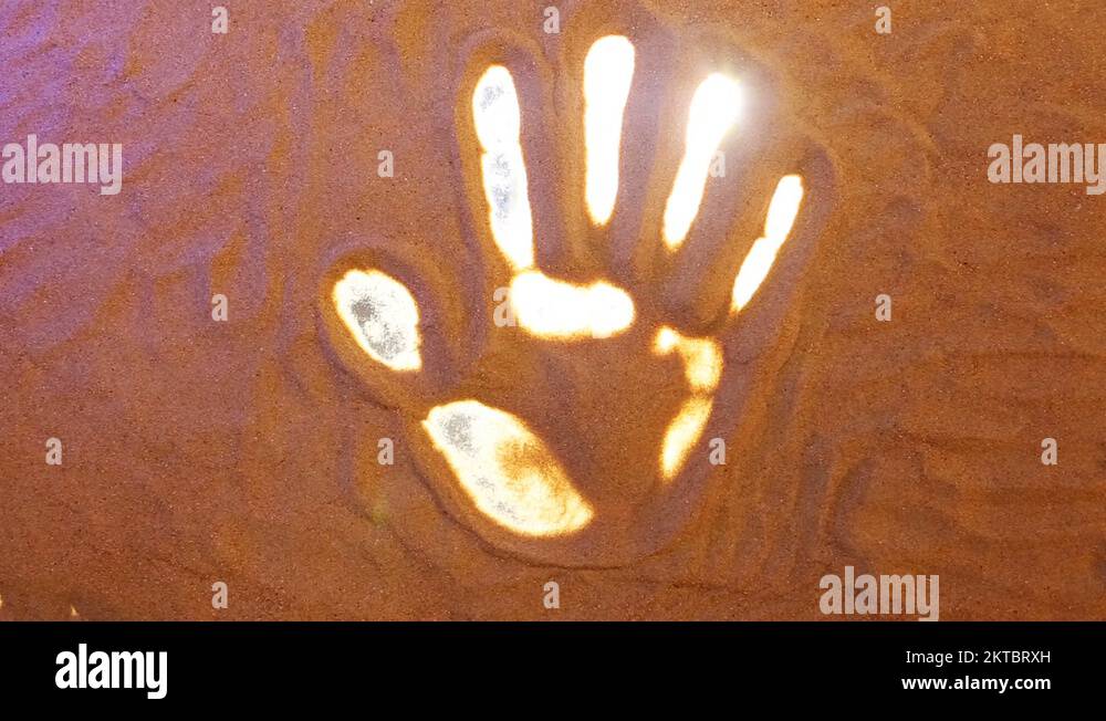 Hand drawing Handprint symbol in the sand. Beach background. Top view ...