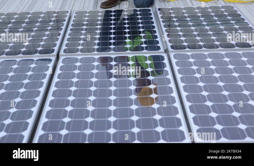 Contractor on industrial rooftop checks solar panels Stock Video Footage - Alamy