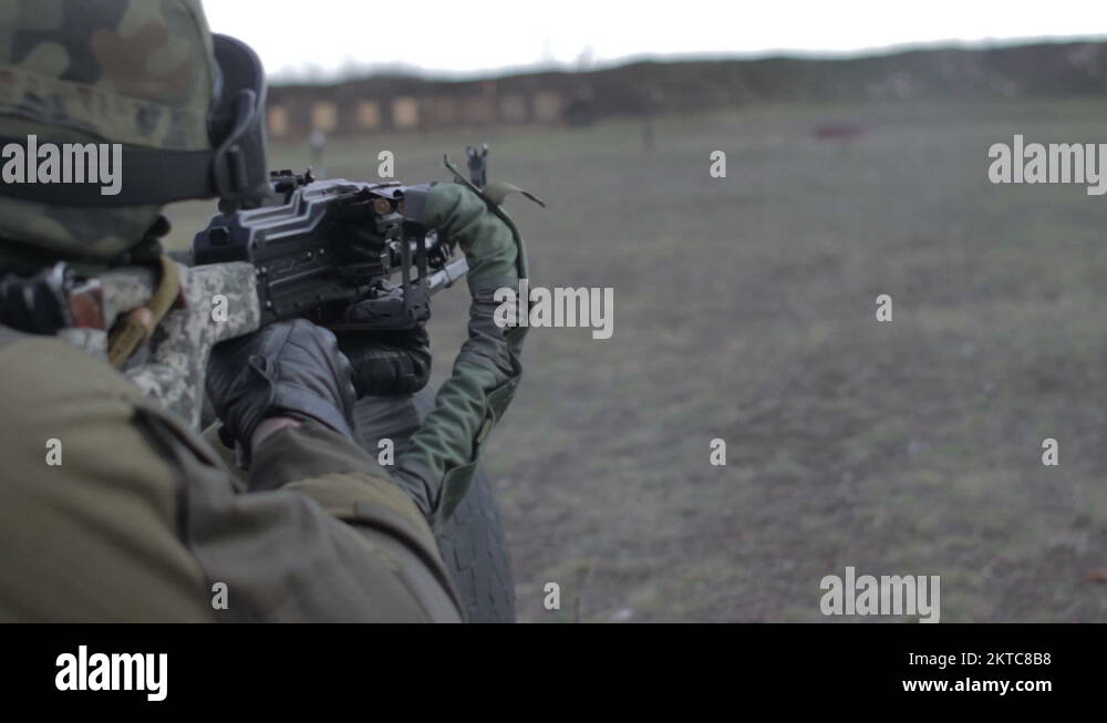 A soldier with a machine gun on a military firing range shooting at a ...
