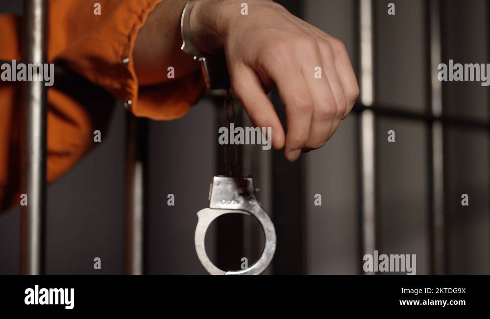 Prison cells in Jail - Handcuff dangling from man's arm in cell Stock ...
