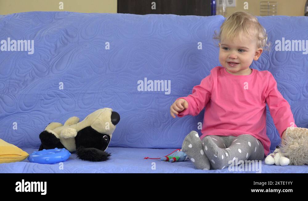 Soft toys rain falling on laughing cute girl sitting on sofa Stock ...