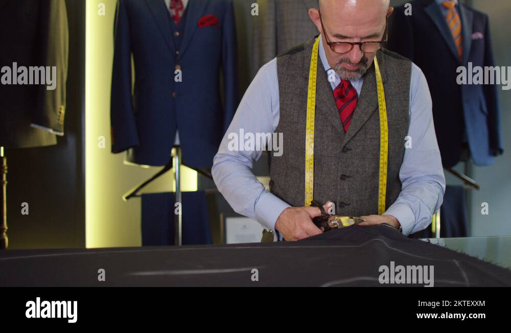 4K Tailor working in his shop, drawing & cutting templates from piece ...