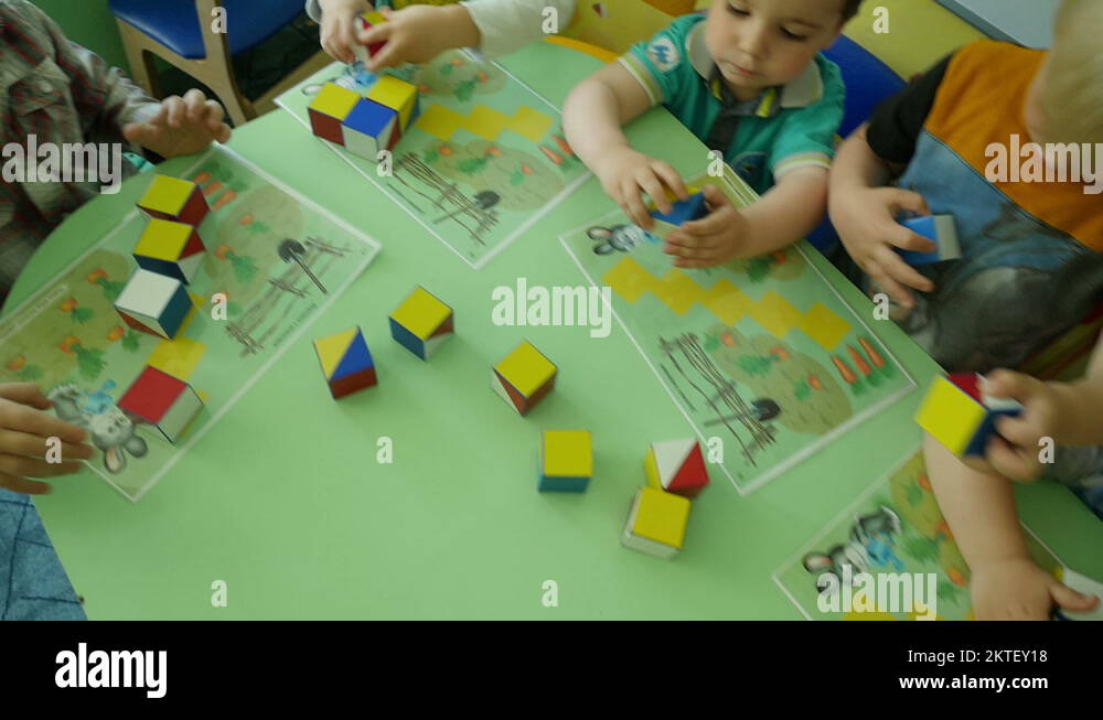 Little children playing with coloured cubes in the kindergarten, Full ...