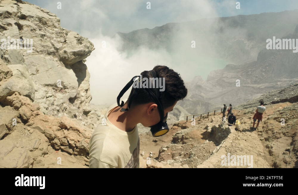 Teenager in gas mask walking down Ijen volcano crater in Java ...