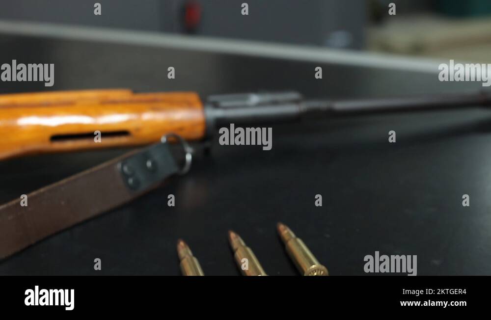 Pan over the body of an assault rifle, down to reveal three rounds of ...