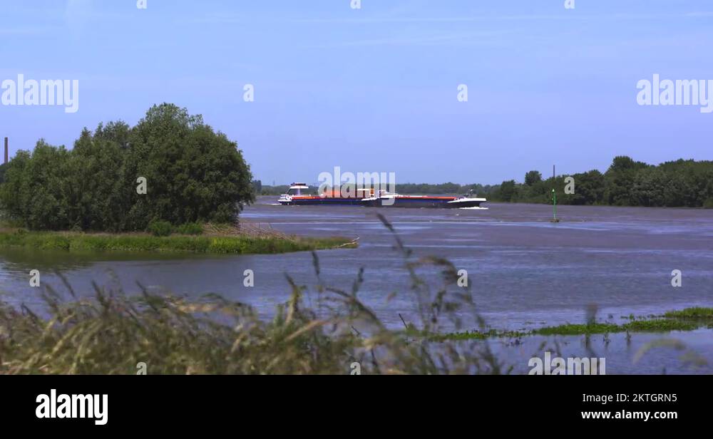 Pusher vessel with two loaded barges maneuvers upstream on inland ...