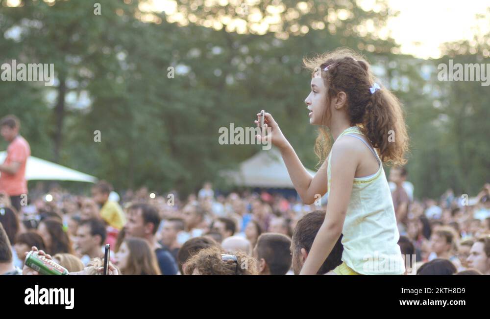 Little cute kid girl fan concert spectator sit on father shoulders to ...