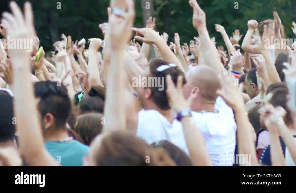 Cheering fan spectators crowd people by concert stage dancing enjoying ...