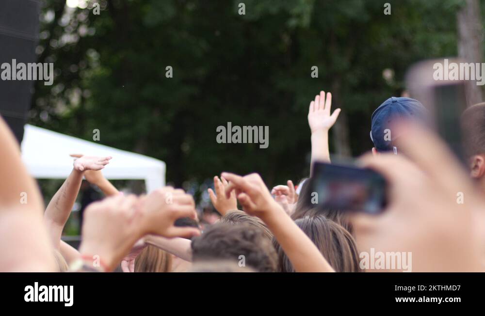 Crowd people spectators young fans open air concert raise wave hands up ...