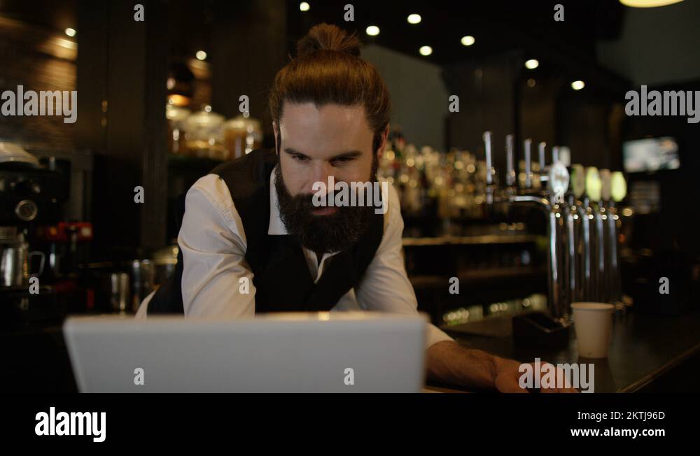 4K Bar owner working on laptop with female employee working in ...