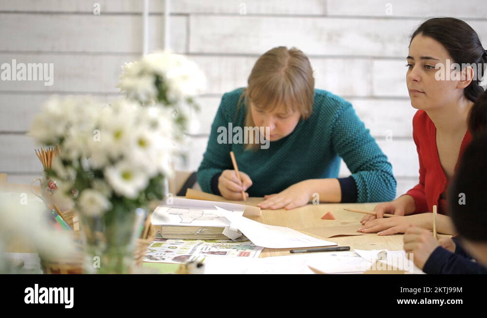 Women create drawings in art studio sitting around wooden table Stock ...