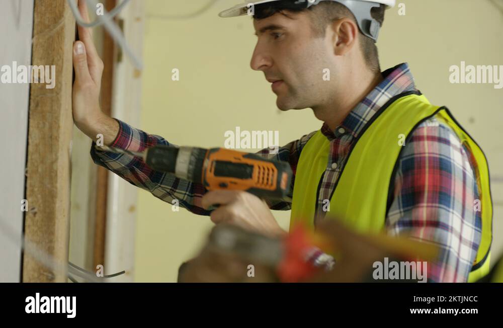 4K Construction workers on a building site drilling & checking wiring ...