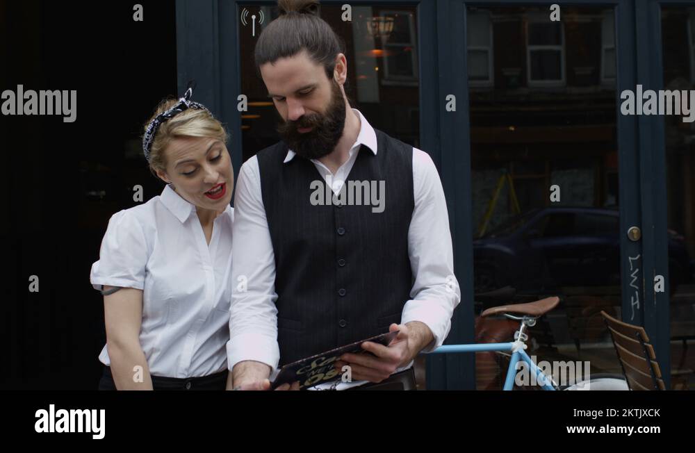 4K Smiling bar or cafe owners hold up a sign to show they are open for ...
