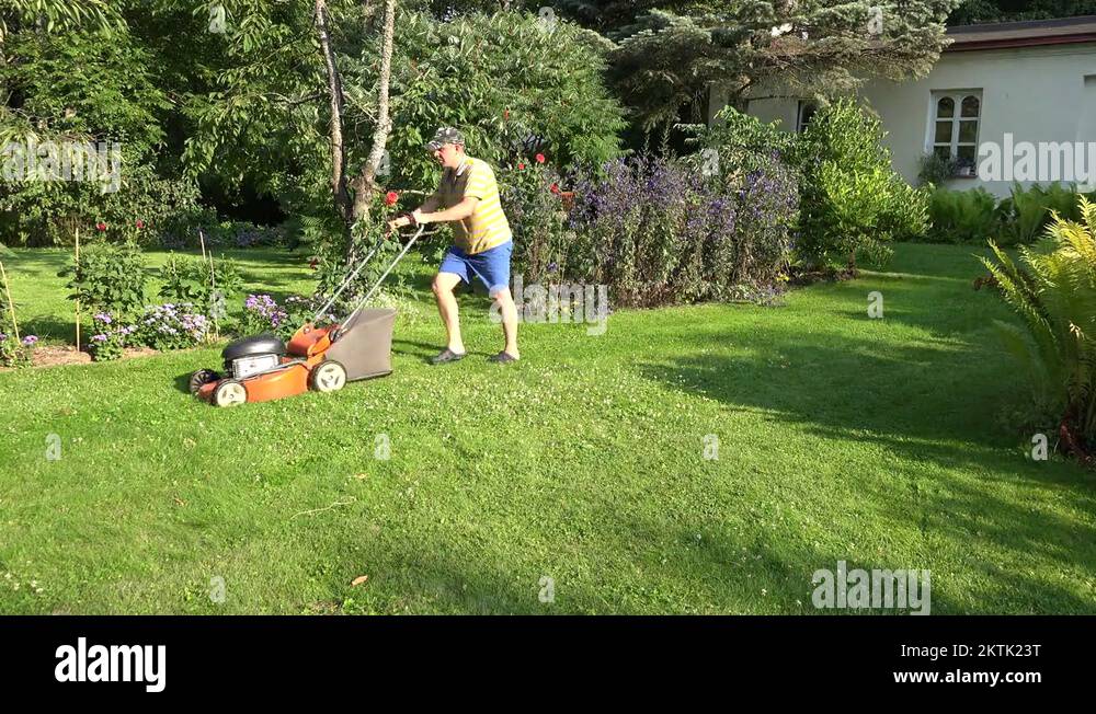 male landscaper man mowing lawn in the yard of his homestead house. 4K ...