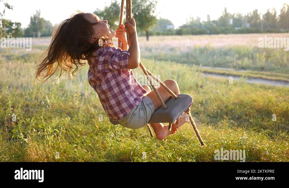 Happy cute little child girl have fun sway spin on a swing on nature ...