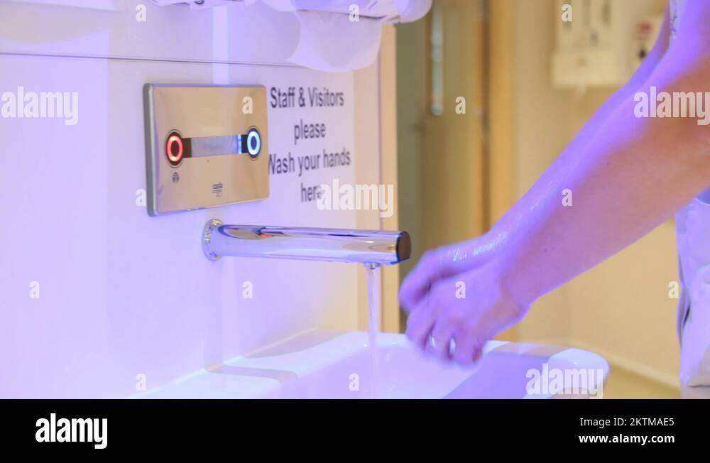 Hospital worker using a hand washing station at a UK NHS hospital Stock ...