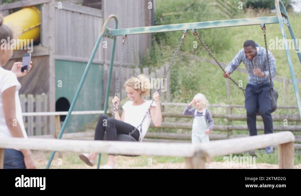 4K Family in playground, dad jumping off swing & little girl taking ...
