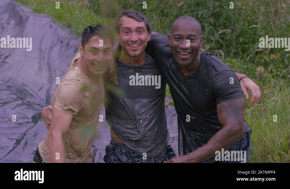 4K Portrait smiling mud race runners after slide down hill into cold ...