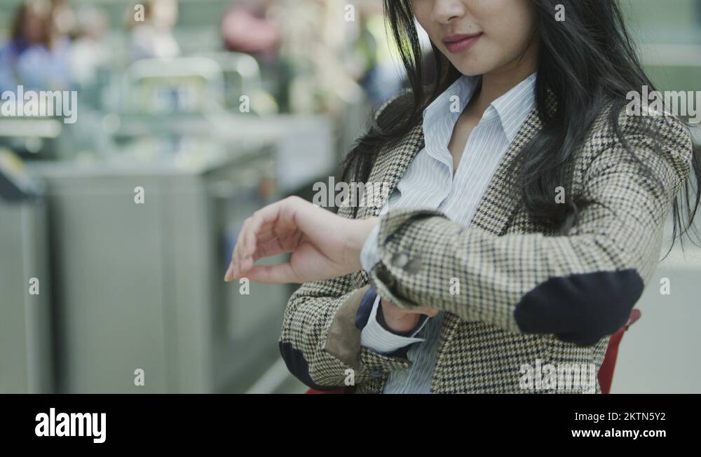 Attractive young woman at a railway station checks her watch as she ...