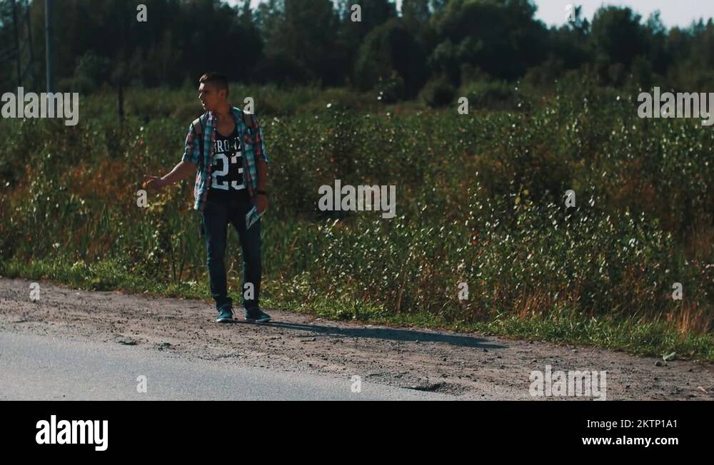 Young boy hitchhiking at roadside. Traveler. Thumb up. Map in hands ...